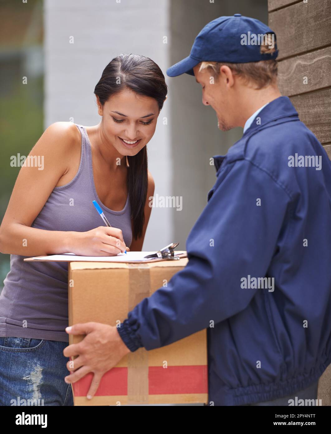 Smile, young woman and signing delivery from postman or exchange for logistics or keeping his ...