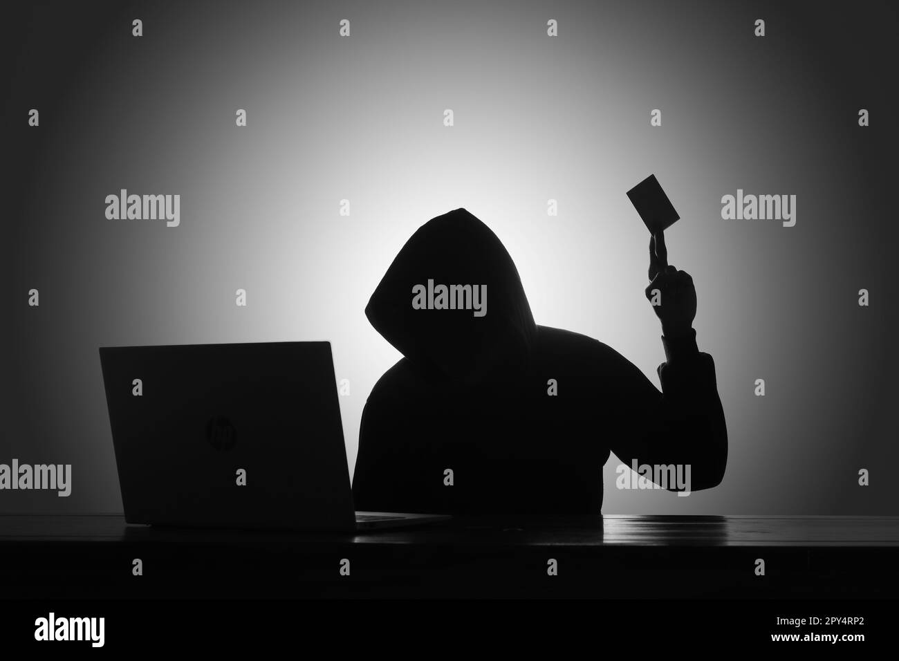 Mysterious Man Wearing Black Hoodie Using Laptop And Holding Credit Card In The Dark Room