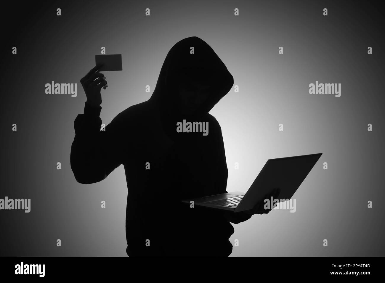 Mysterious Man Wearing Black Hoodie Using Laptop And Holding Credit Card In The Dark Room
