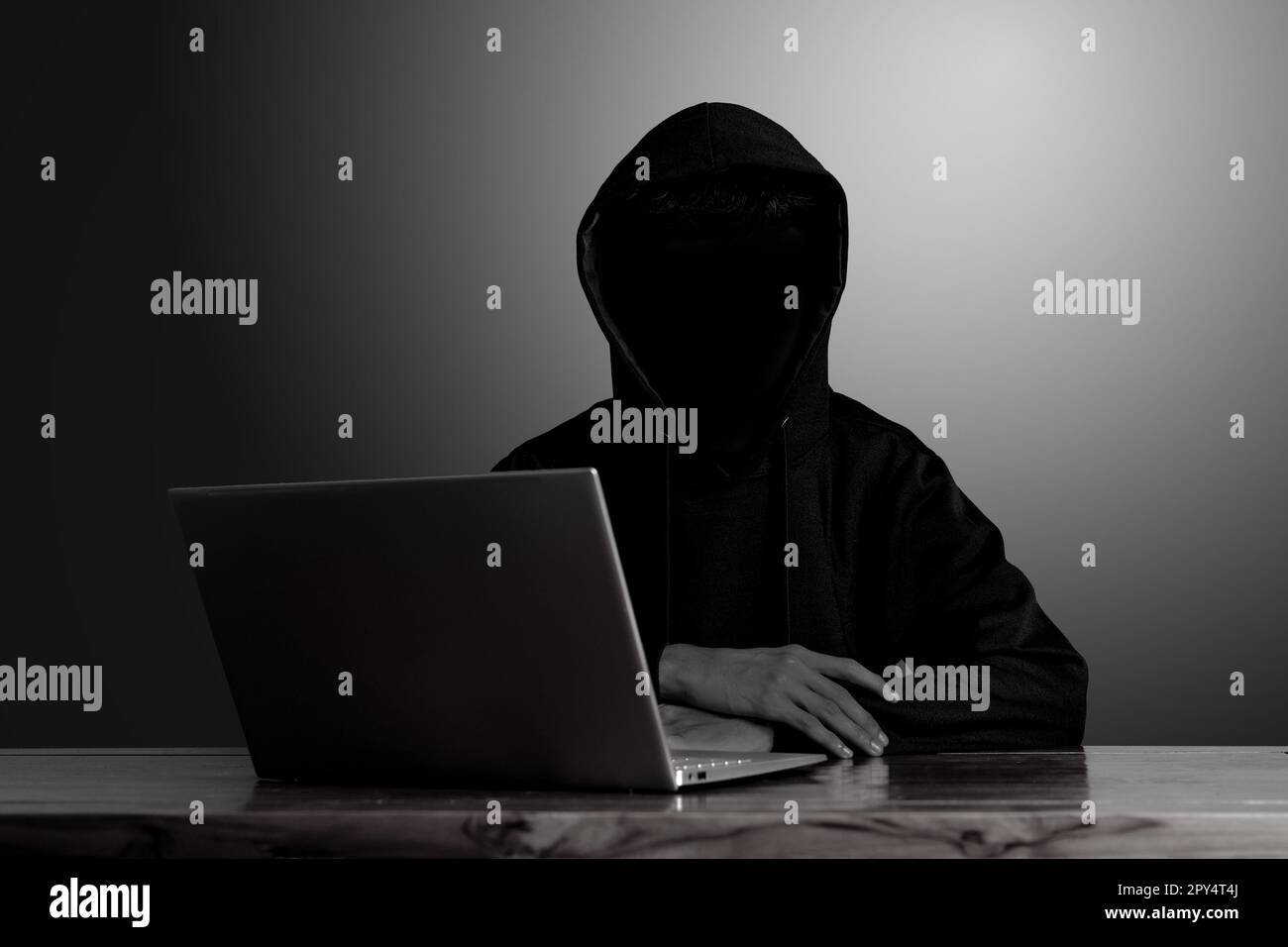Mysterious man wearing black hoodie using laptop in the dark room ...