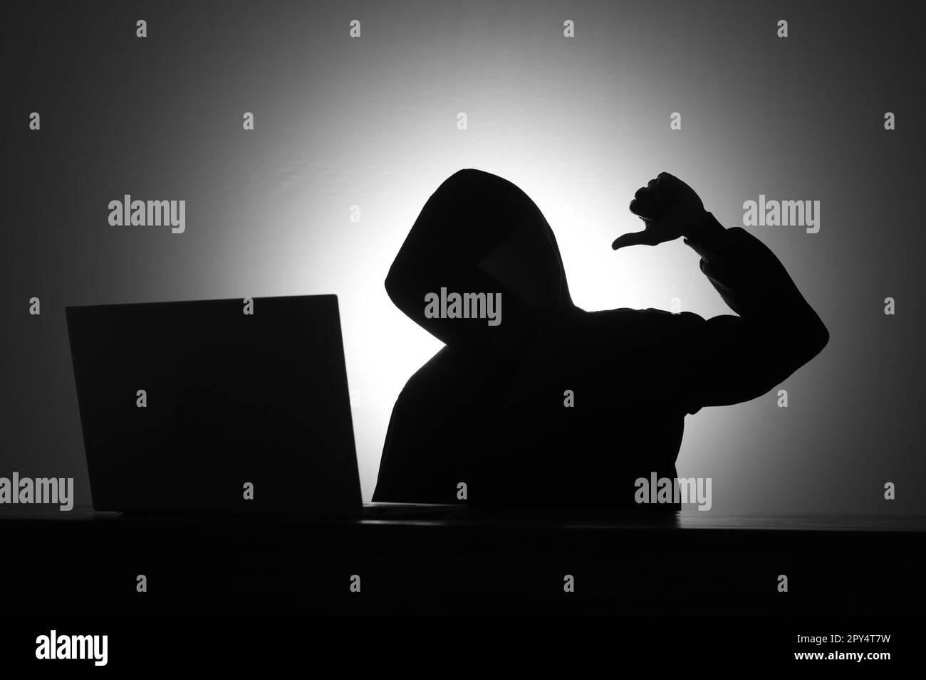 Mysterious man wearing black hoodie using laptop while mocking someone ...