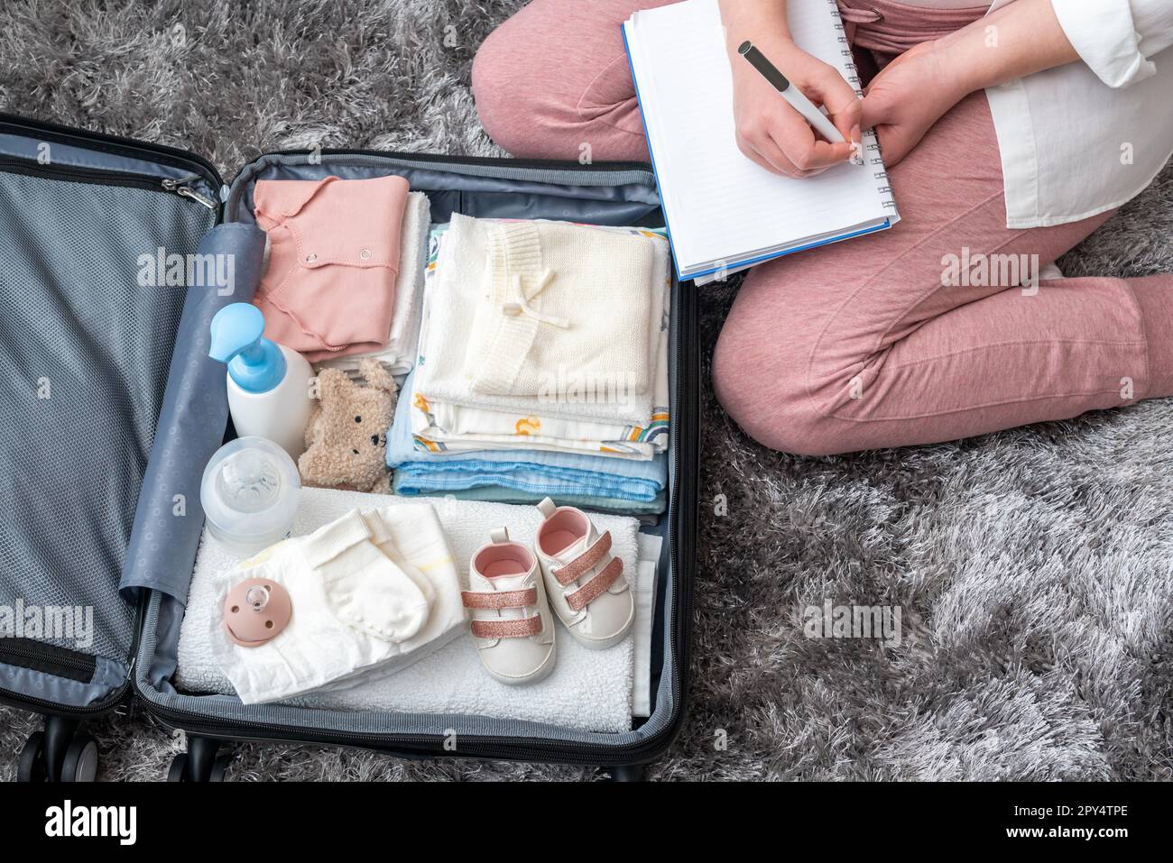 Top view of pregnant woman writing packing list for maternity hospital ...