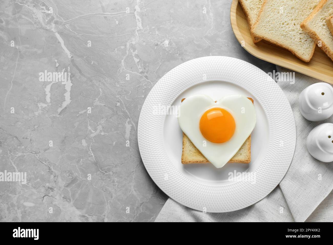 Heart shaped fried egg served on grey marble table, space for text Stock Photo - Alamy