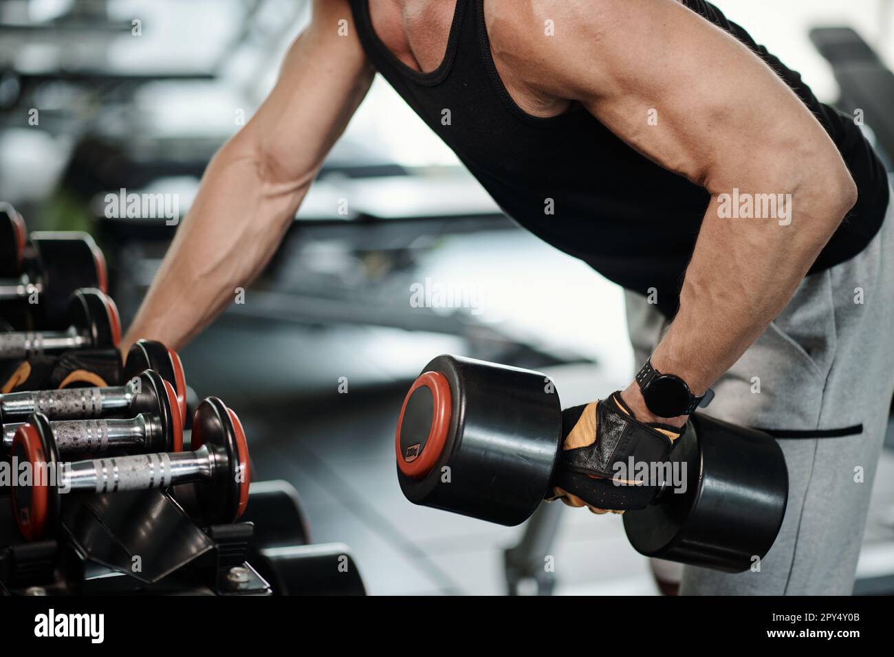 Fit man lifting heavy dumbbells when working on upper body Stock Photo ...