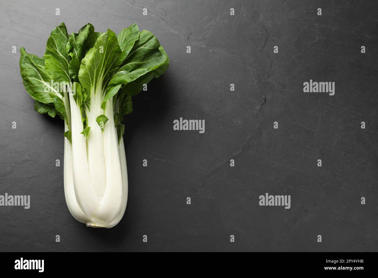 Fresh green pak choy cabbage on black table, top view. Space for text ...