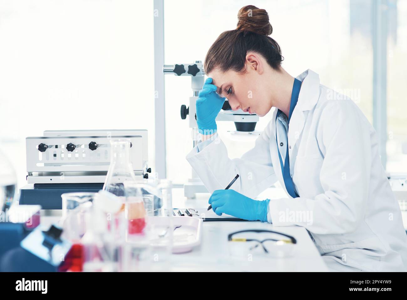 My brain is working overtime. a tired young female scientist making ...