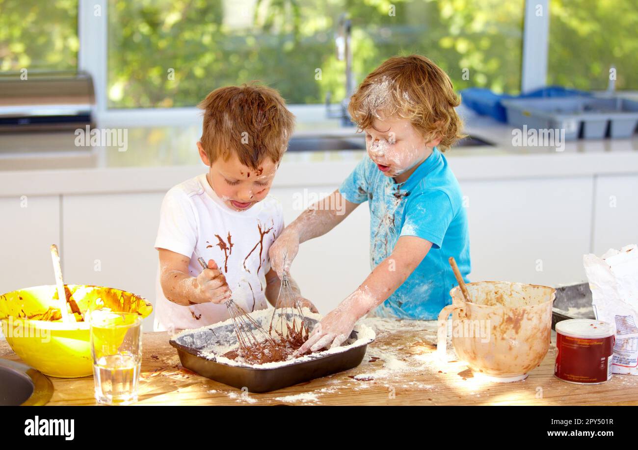Baking, children and messy friends in the kitchen together, having fun with ingredients while ...