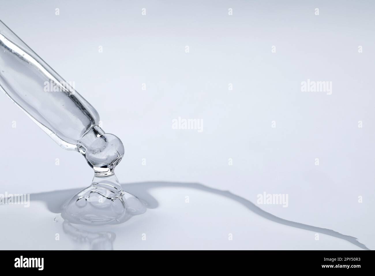 Dripping face serum from pipette on white background, closeup. Space ...
