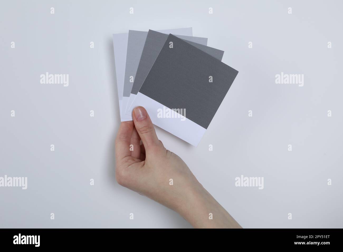 Woman with color sample cards choosing paint shade near white wall ...