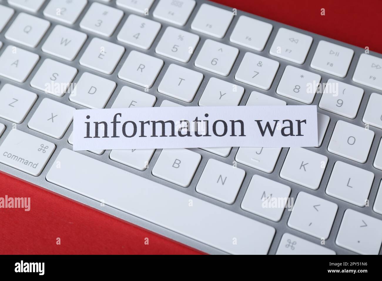 Paper card with words Information War and keyboard on red background ...