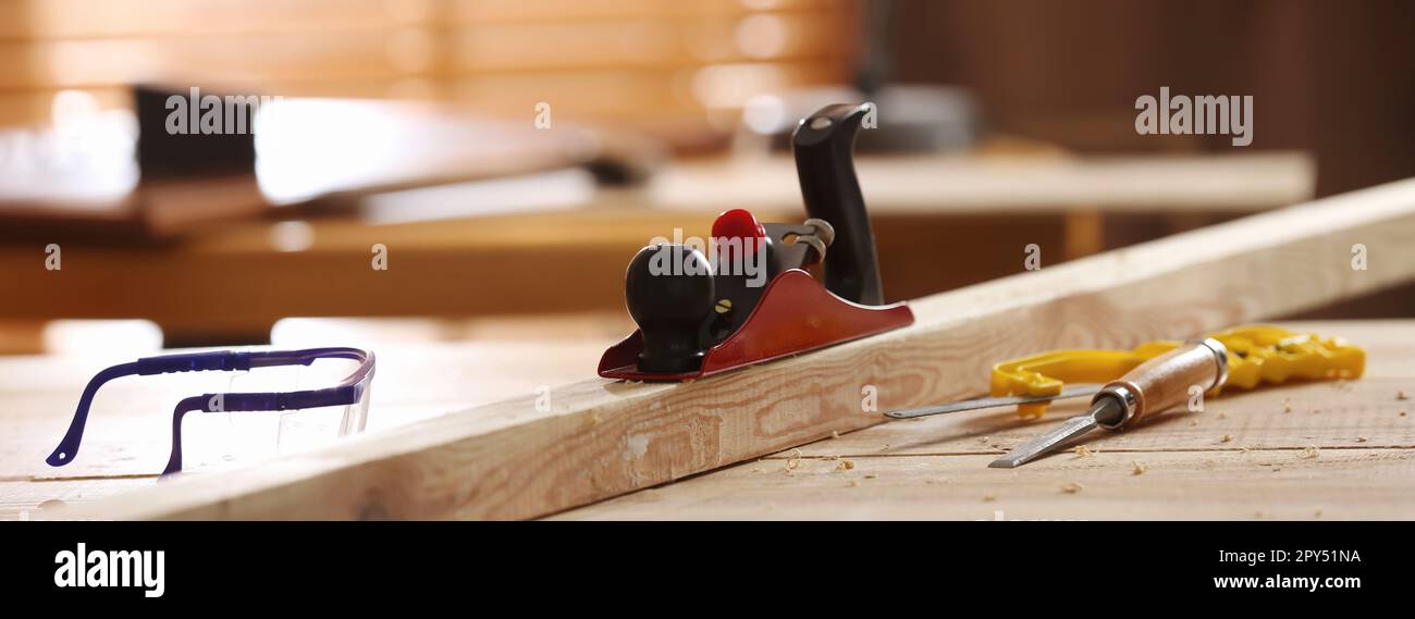 Different carpenter's tools and wooden bar on table in workshop. Banner ...