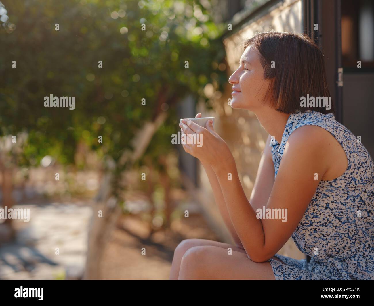 Woman is drinking coffee , morning routine near her Tiny house. First ...