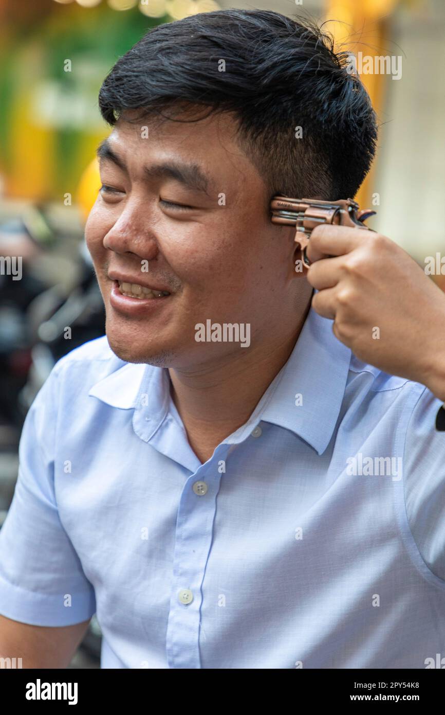 Vietnamese man posing with toy gun cigarette lighter poining at his ...