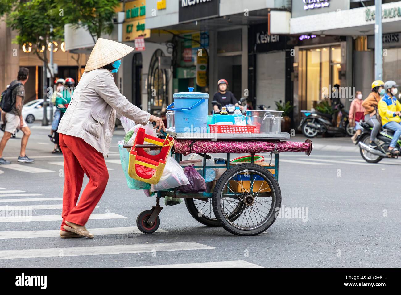 Traditional street vendor wearing bamboo hat and pushing cart, Ho Chi ...