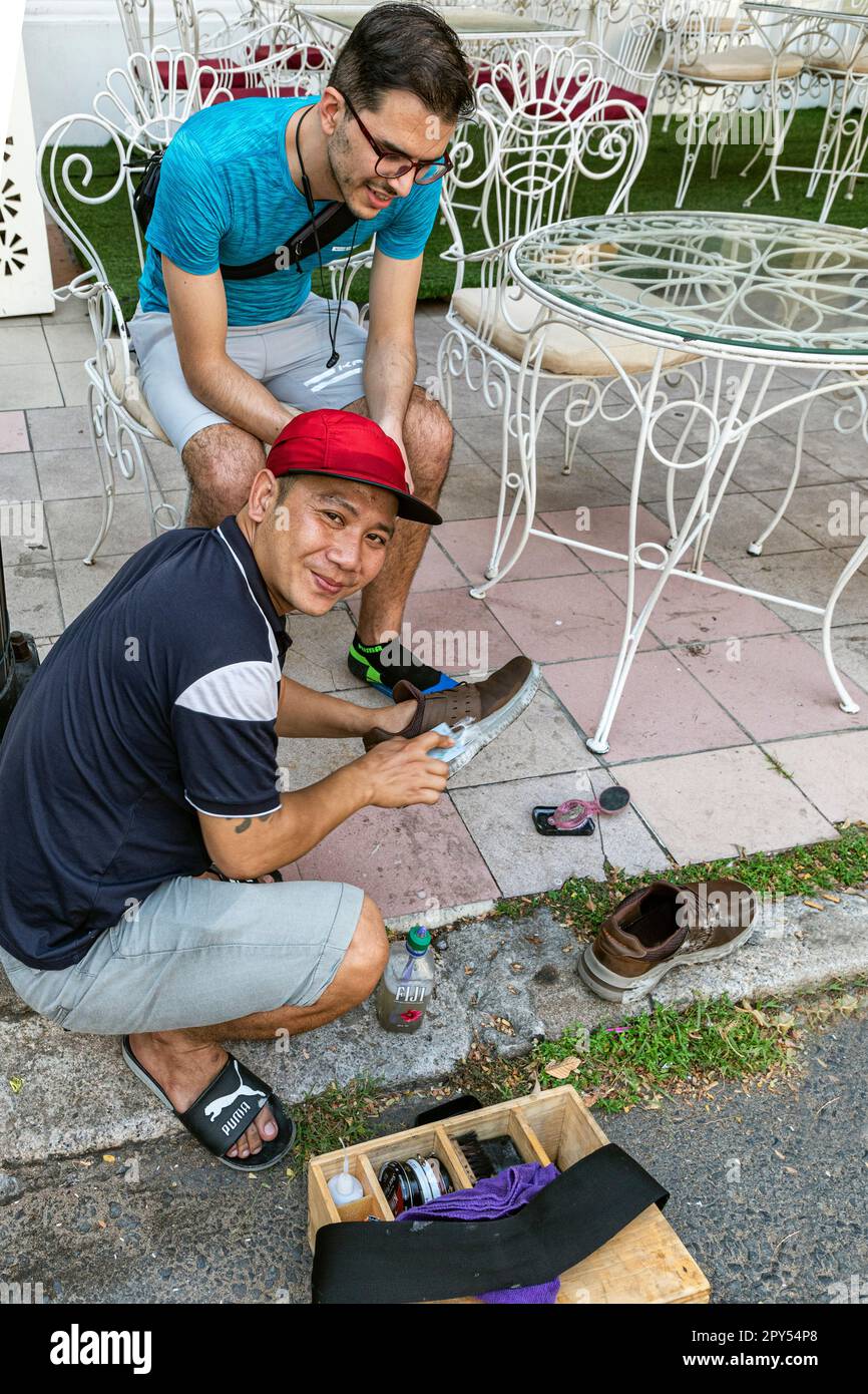 Vietnamese shoe shine boys working on American tourist in Ho Chi Minh ...