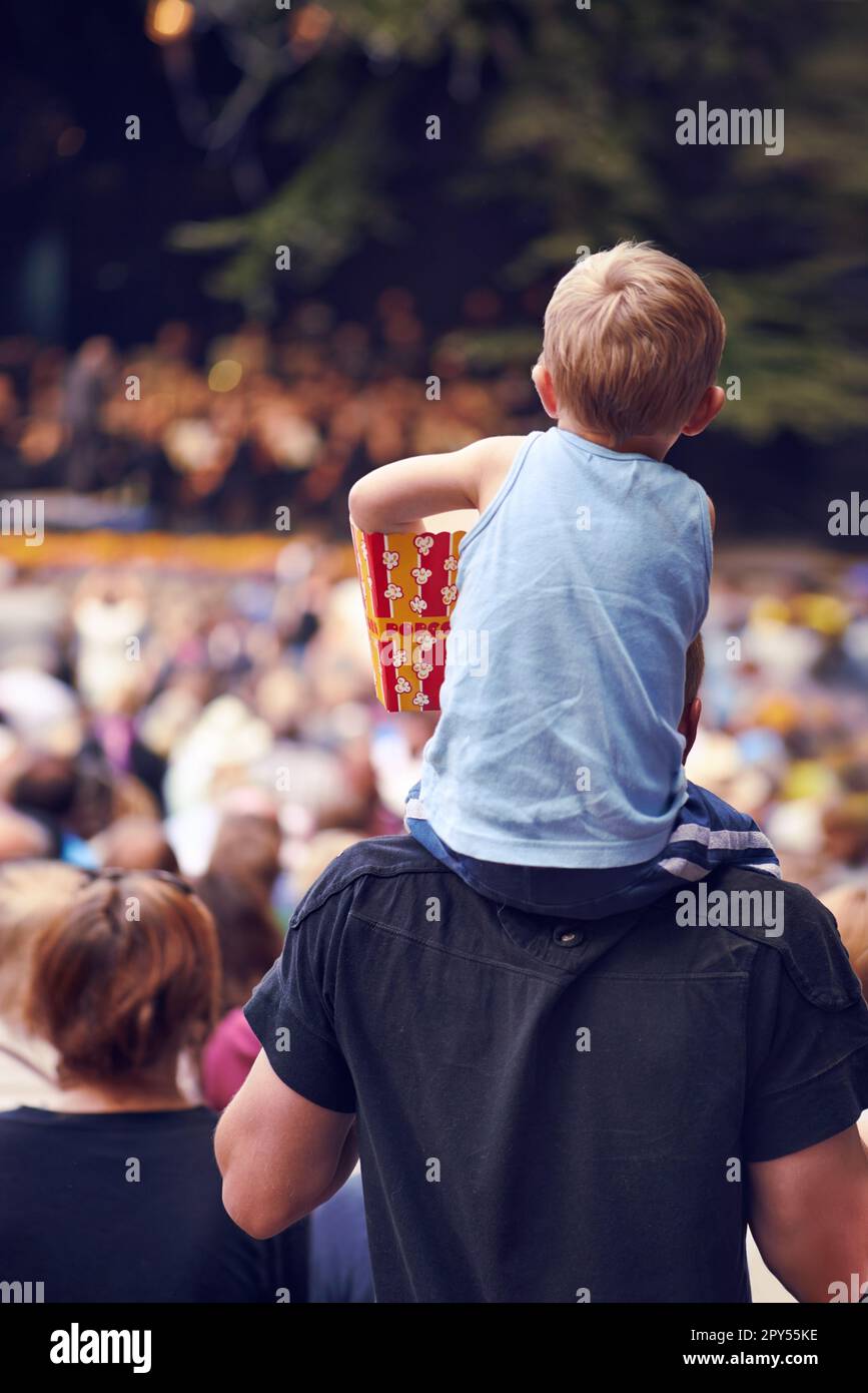 Back, festival and a boy sitting on dad shoulders outdoor at a music ...