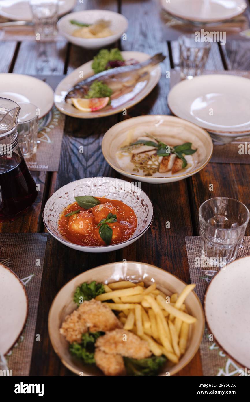 Different kind of food on wooden table in restaurant on terrace. French ...