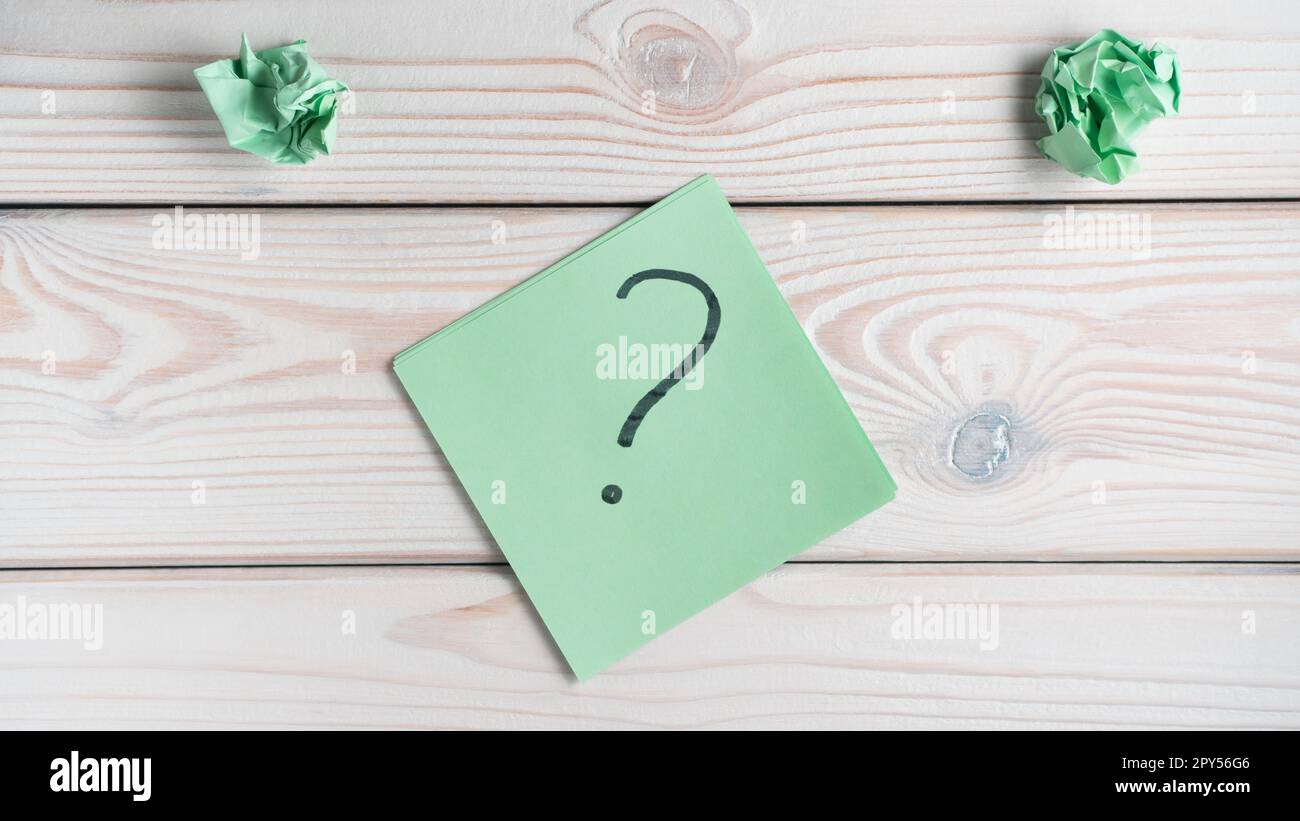 Flat lay of green sticker sticky note with question mark drawn with ...