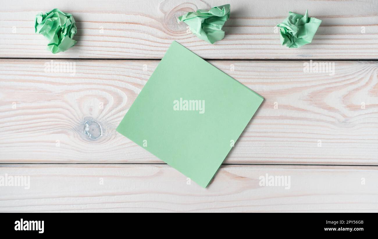 Flat lay of blank green sticker sticky note near crumpled notes on grey ...