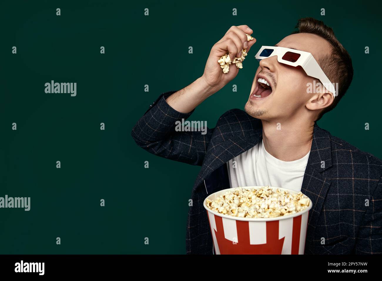 guy in 3d glasses eating popcorn on pink background Stock Photo - Alamy