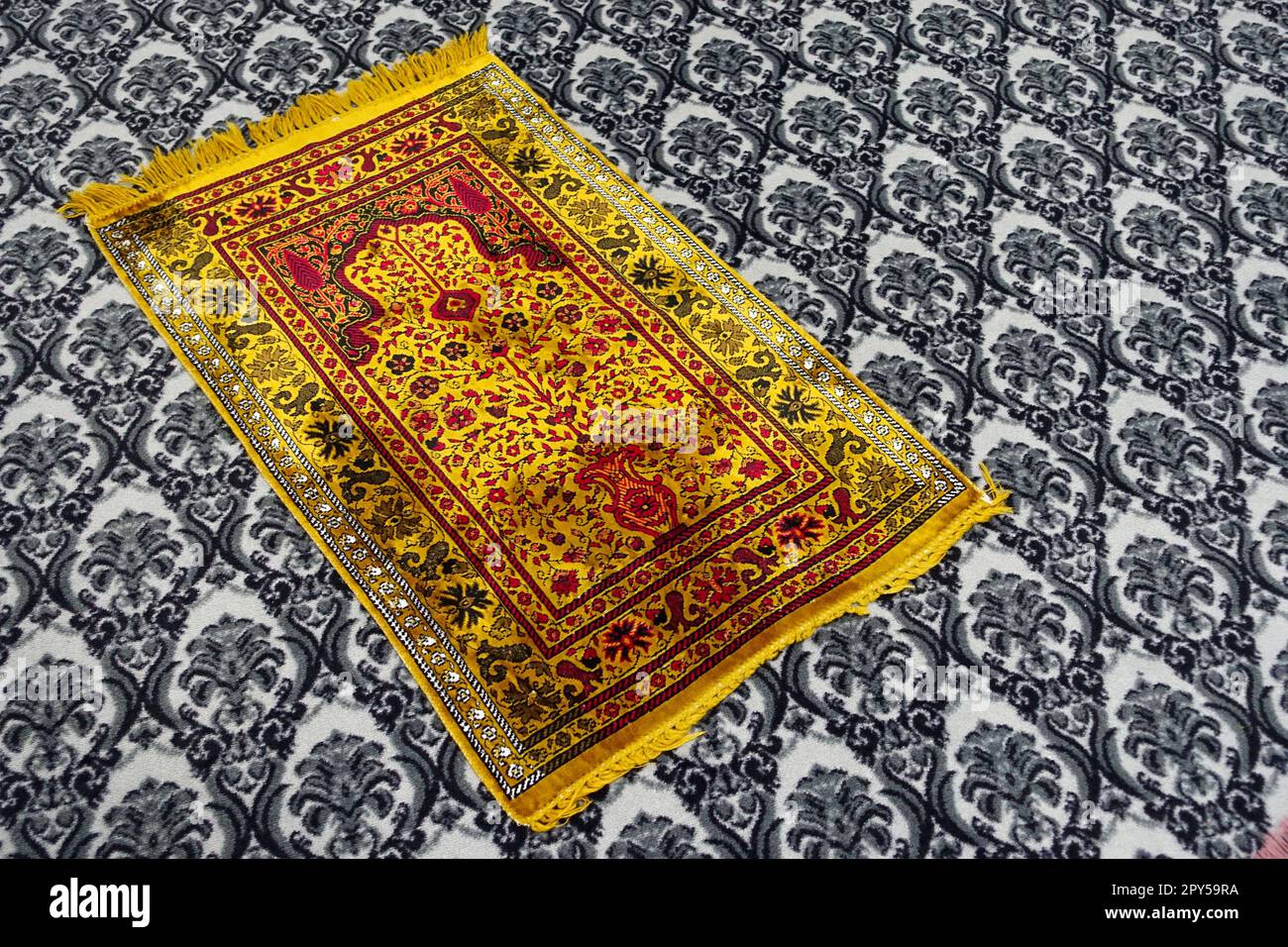 Prayer is performed on the prayer rug laid in the masjid, yellow prayer ...