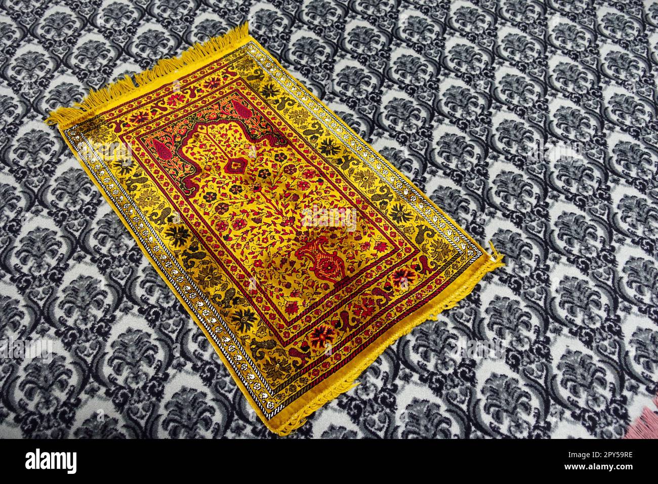 Prayer is performed on the prayer rug laid in the masjid, yellow prayer ...
