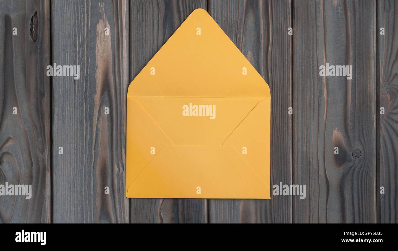 Flat lay of open empty yellow envelope on grey wooden table ...