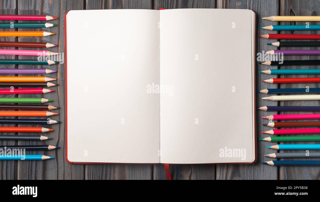 Flat lay of open empty blank notebook between colored pencils in row on ...