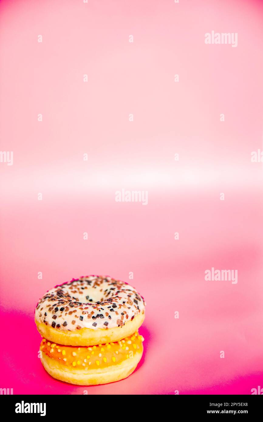 Sweet donuts stacked in a stack on a pink background. Copy space ...