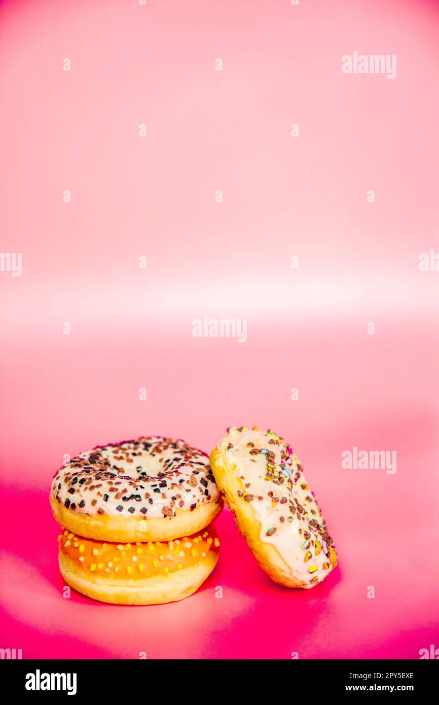 Sweet donuts stacked in a stack on a pink background. Copy space ...