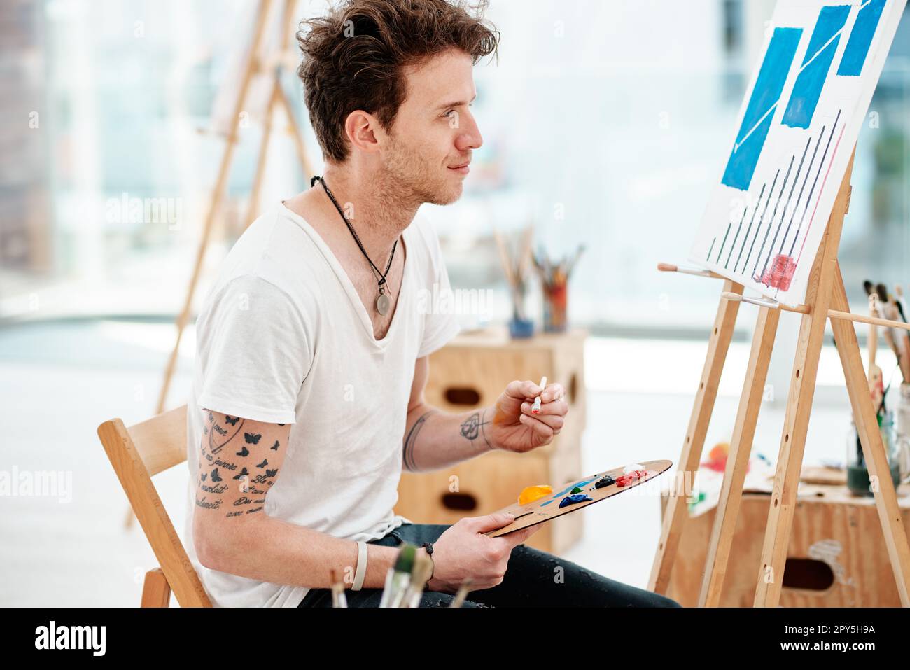Creativity never goes out of style. a handsome young artist sitting ...