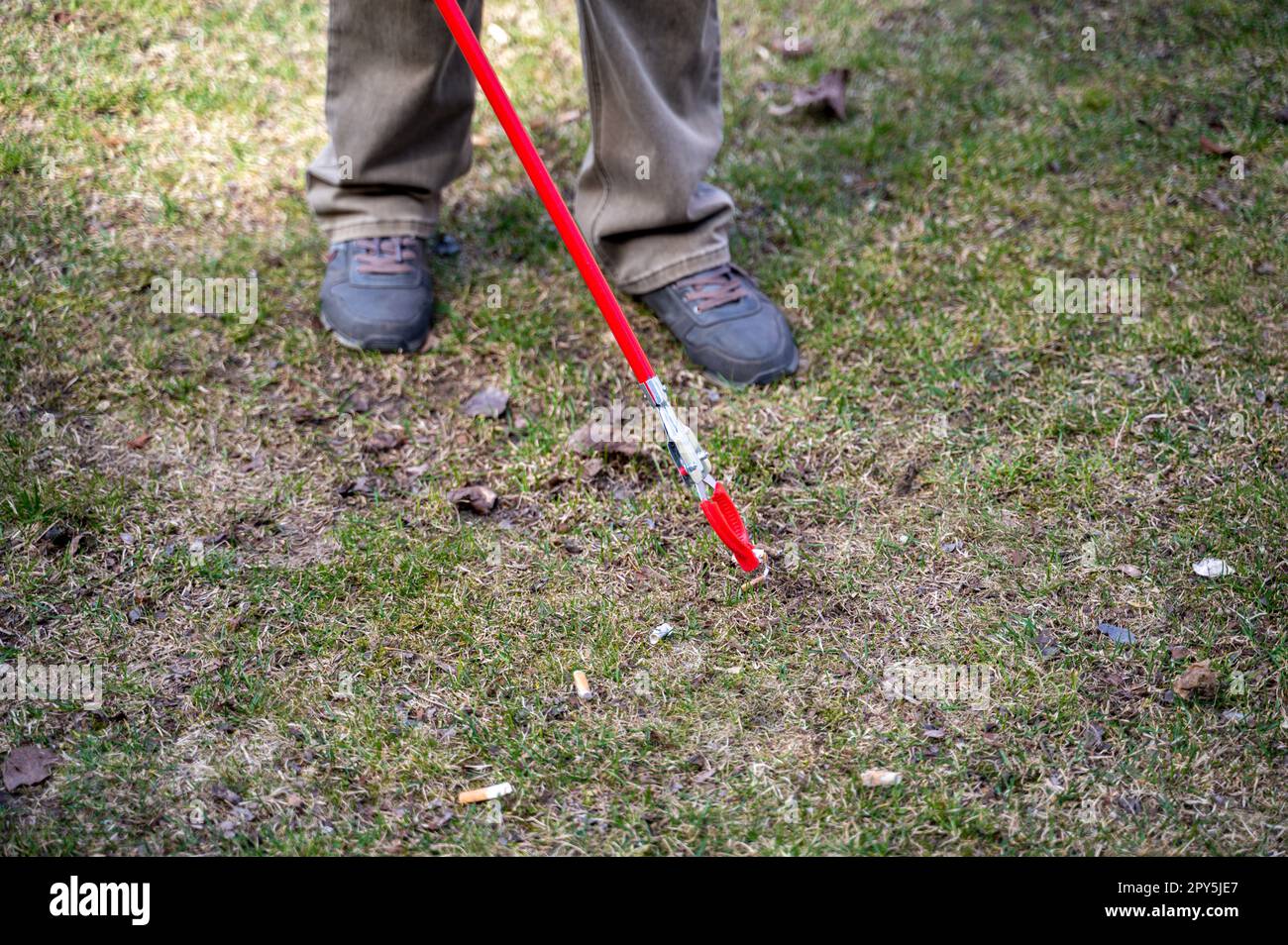 Person with Grabber Reacher Tool picking up cigarette butts from ground ...