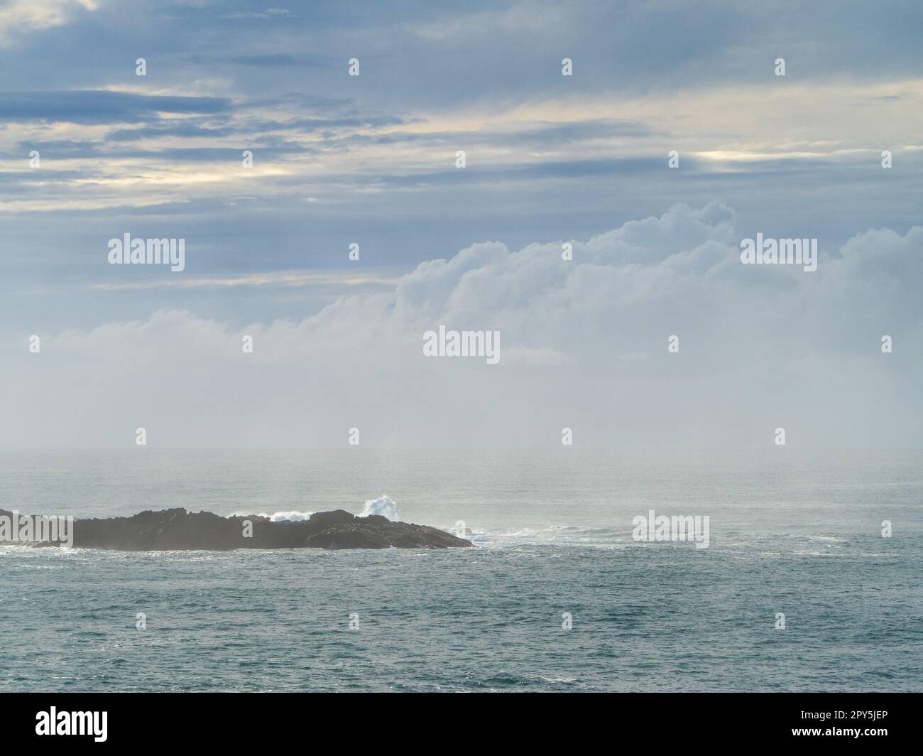 Hazy misty looking ocean scene with majestic clouds, island and sea ...