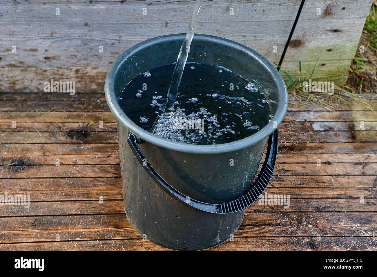 a black plastic bucket is filled with water from the pump Stock Photo ...