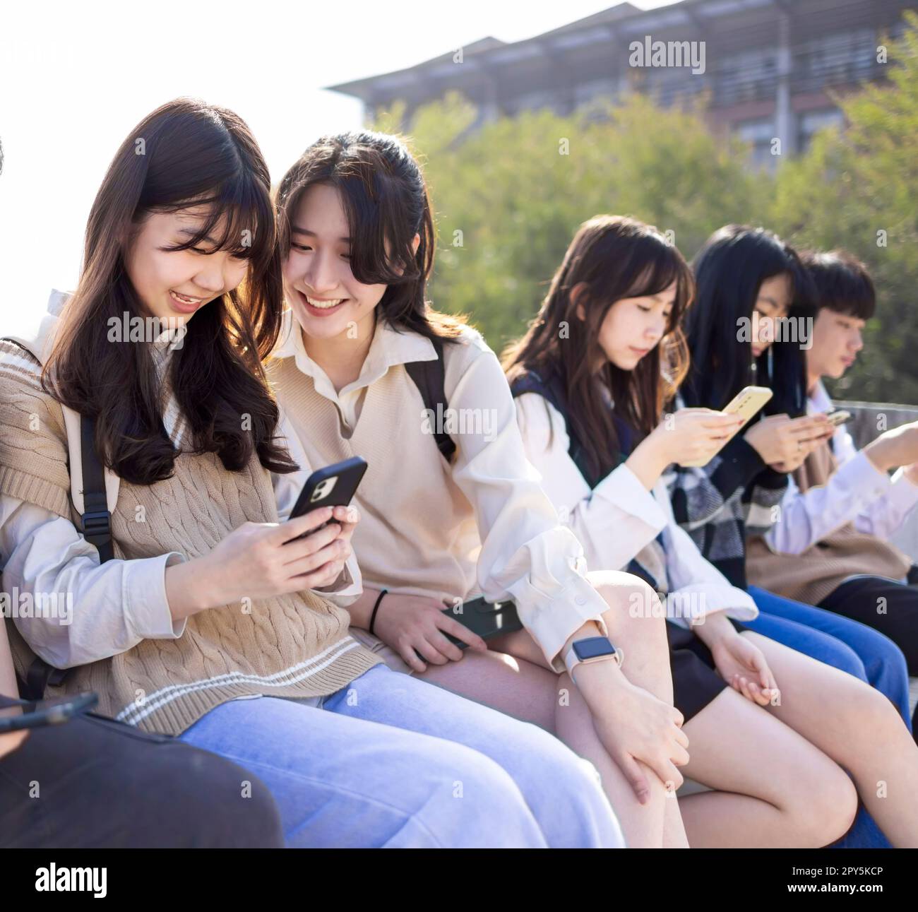 Happy young group using the mobile phones at school Stock Photo - Alamy