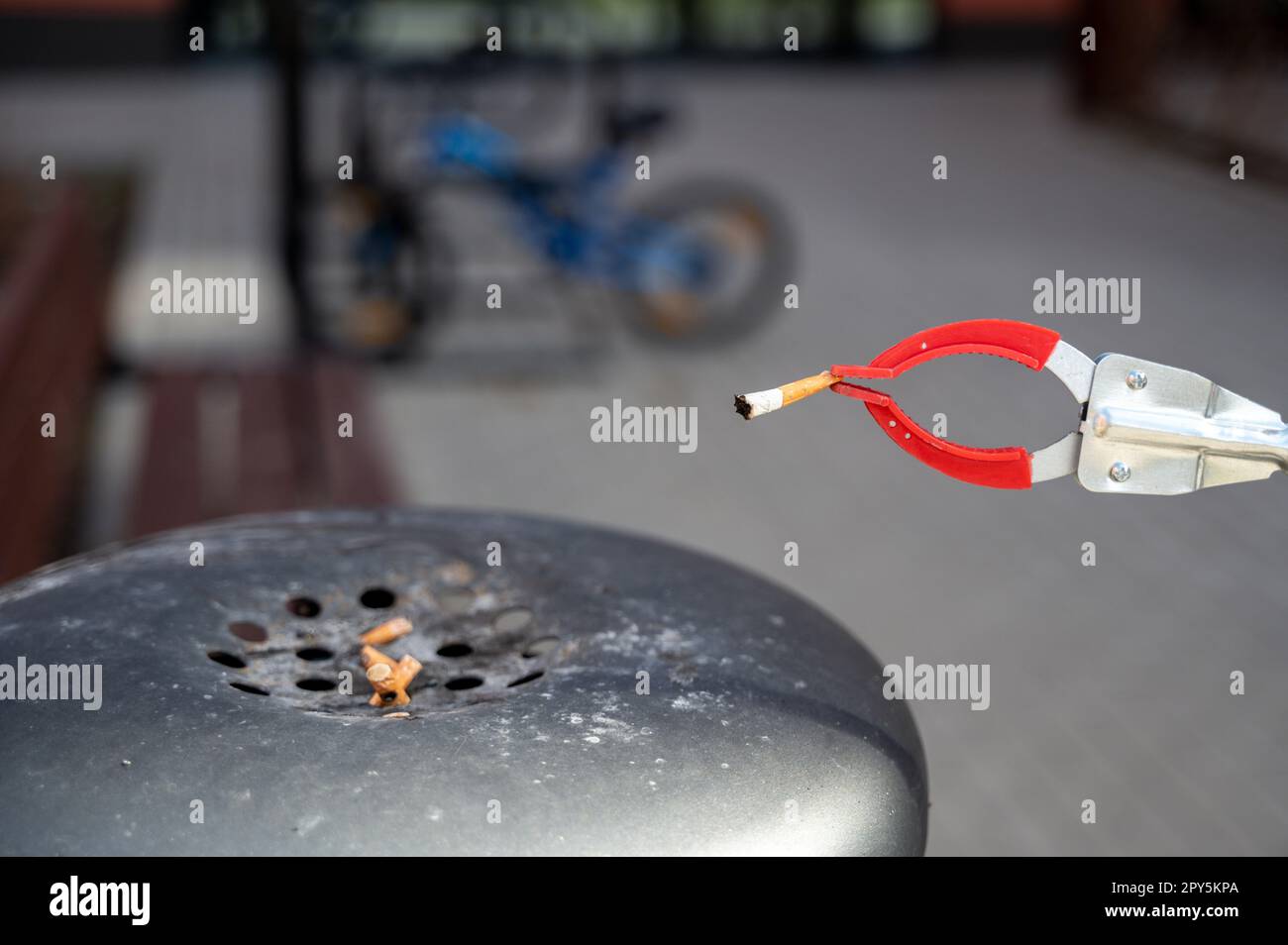 Person with Grabber Reacher Tool putting cigarette butts from ground ...