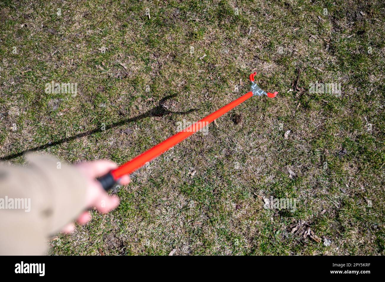 Person with Grabber Reacher Tool picking up cigarette butts from ground ...