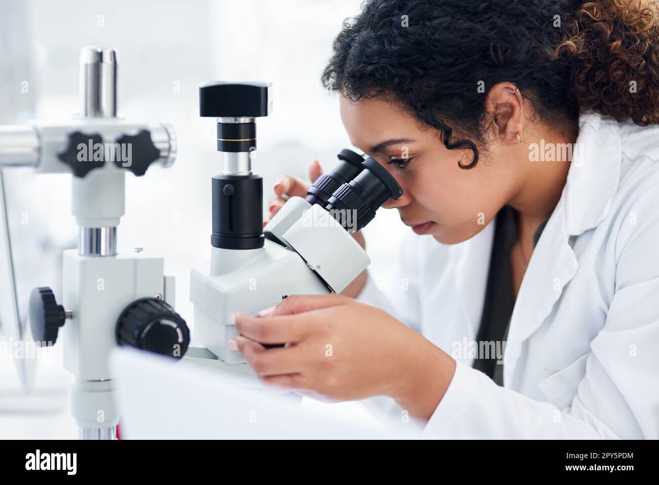 Taking a closer look. a young female scientist using a microscope in a ...