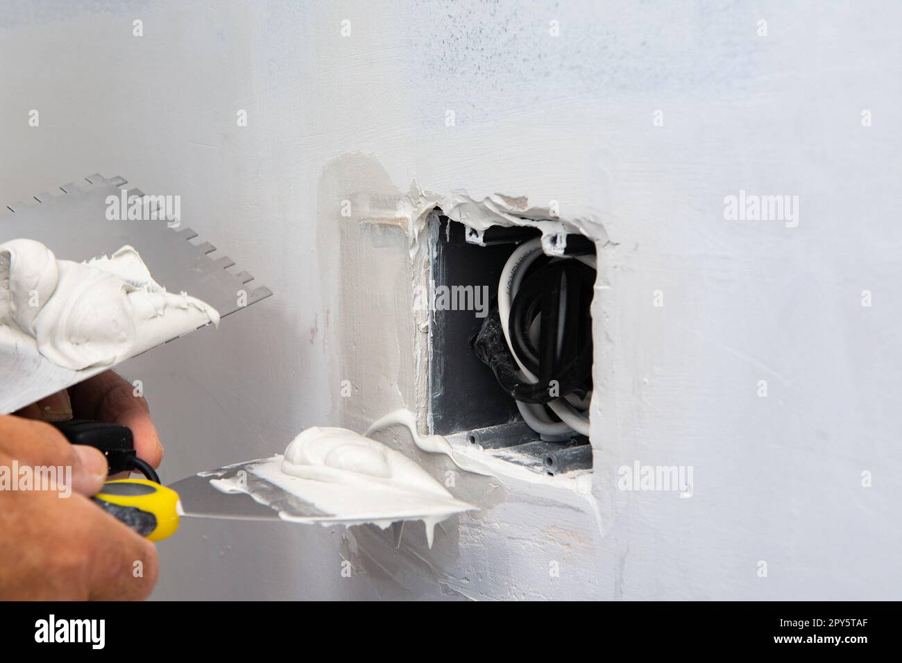 Wall putty repair after installing the socket box Stock Photo - Alamy