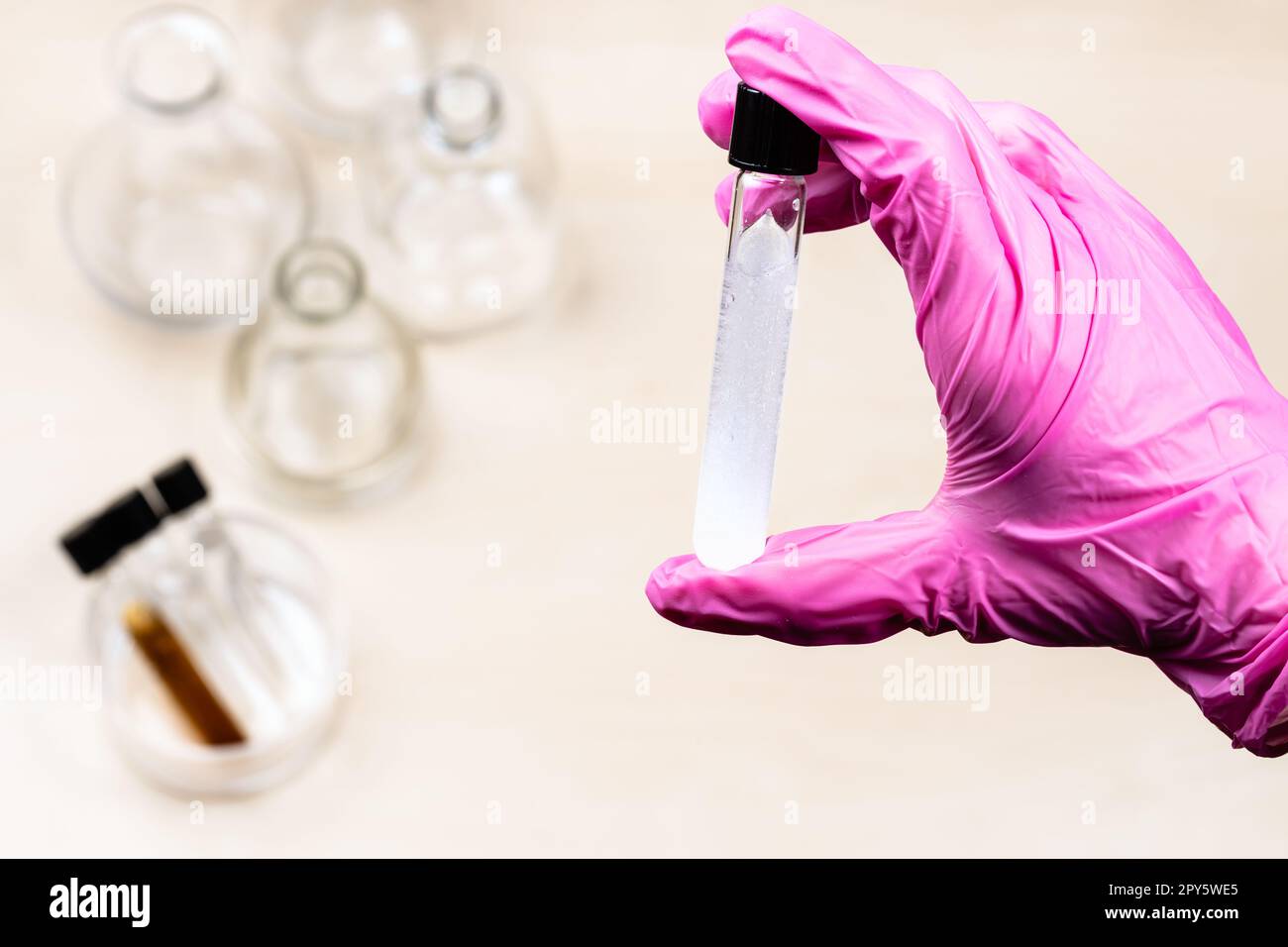 hand holds test-tube over light desk with flasks Stock Photo - Alamy