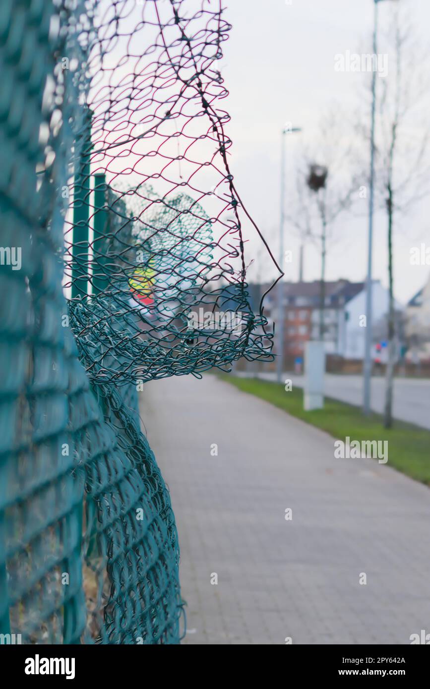 Green damaged wire-mesh fence is ruined after collision with car ...