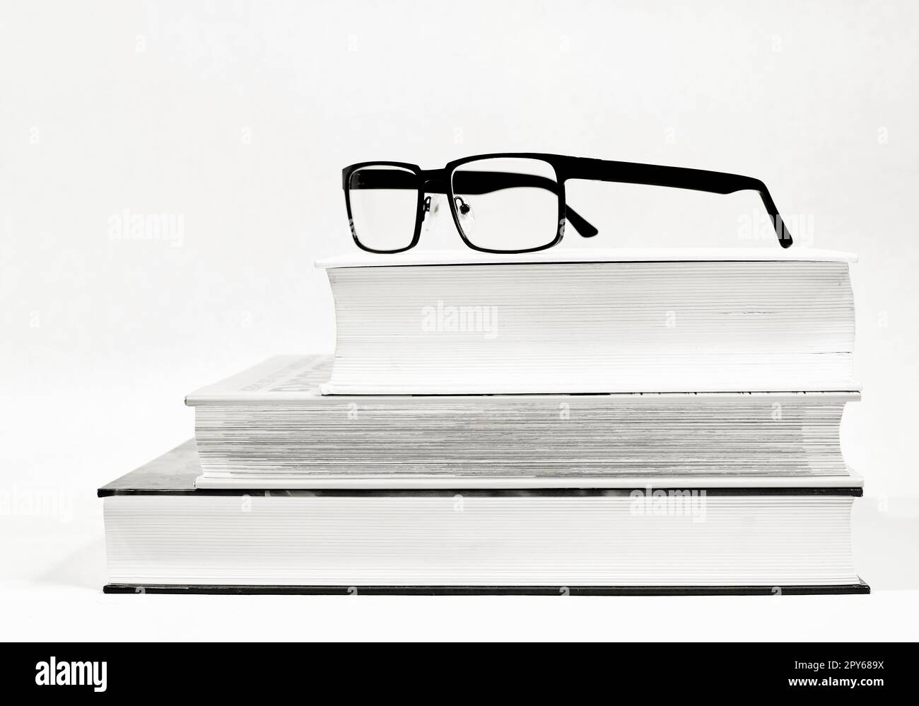 Three thick books and glasses as a visual aid as black and white ...
