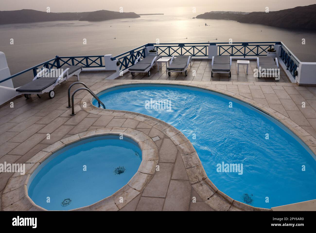 Sun loungers and pools on terrace in the village of Imerovigli with ...