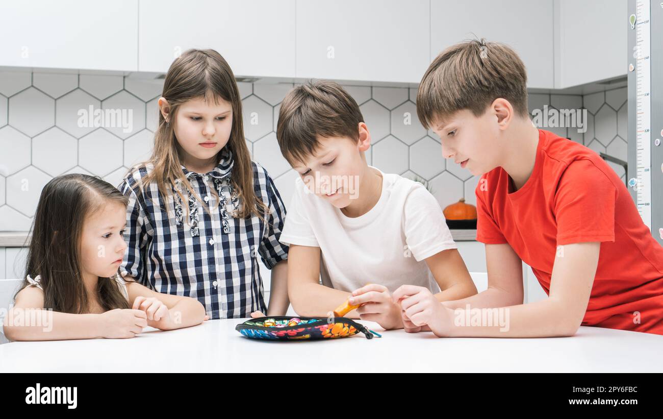 Group of friends play toy fishing on kitchen table. Smart boy hold ...