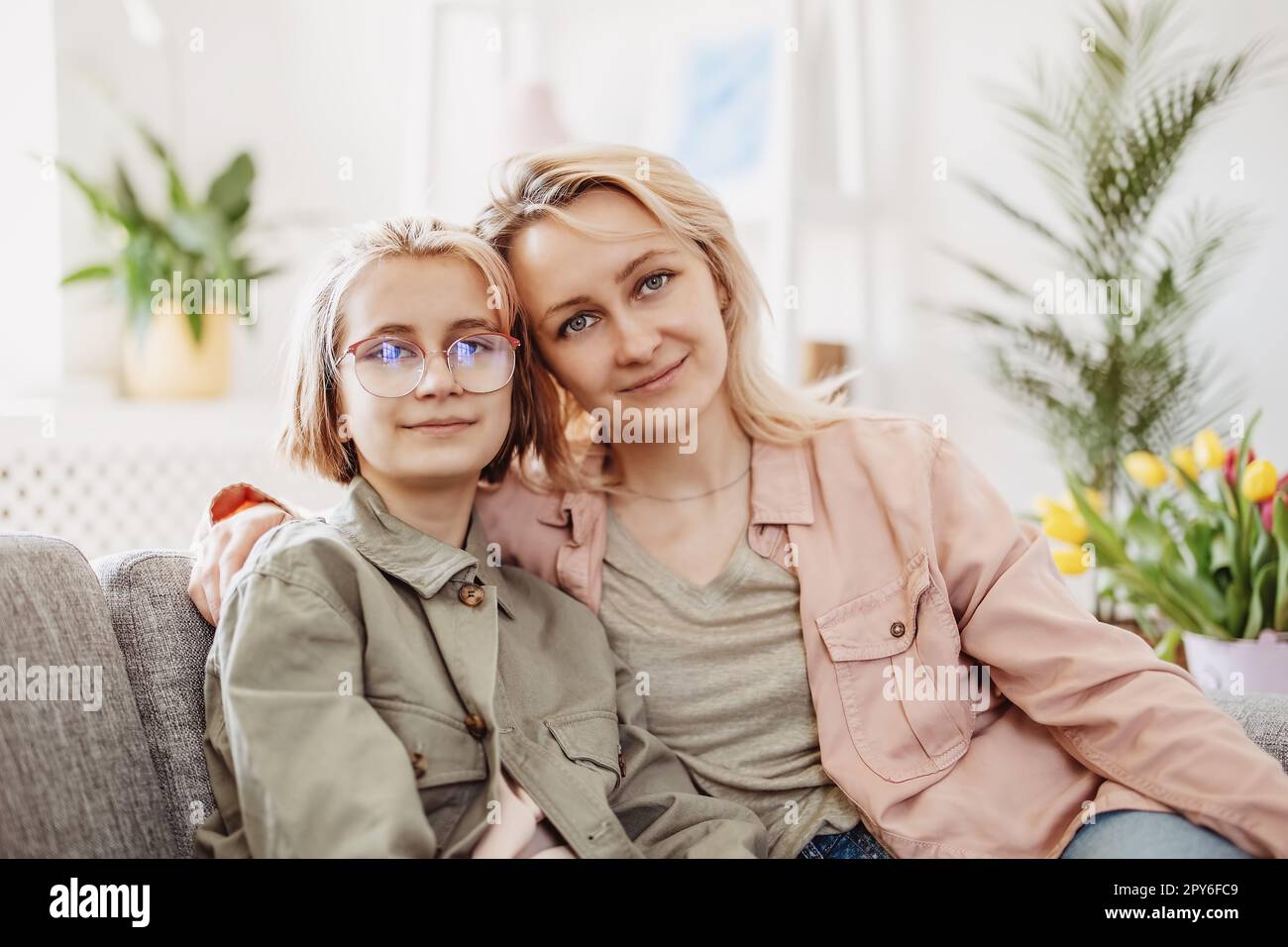 Mother and daughter sitting on the sofa indoor and embracing Stock Photo - Alamy
