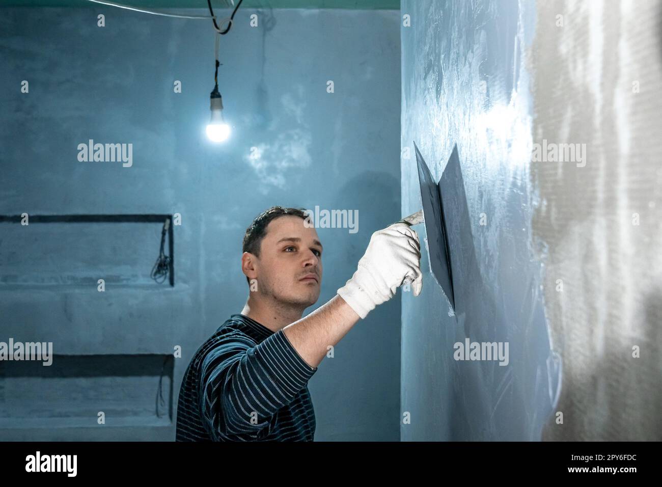 man applies insulation to a bathroom wall with trowel Stock Photo - Alamy