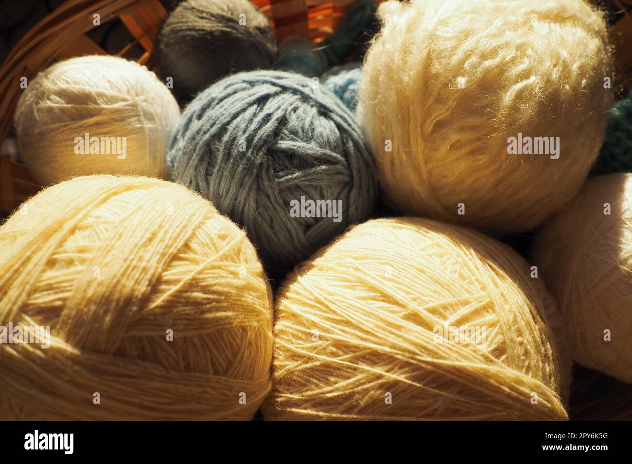 White, beige and blue woolen and acrylic threads wound into a ball or ...