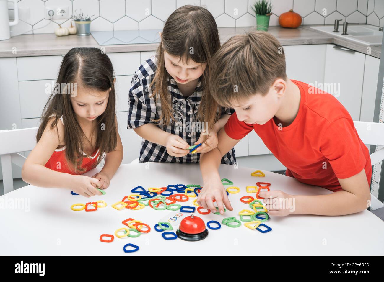 Funny school kids play toy constructor standing above kitchen table and ...