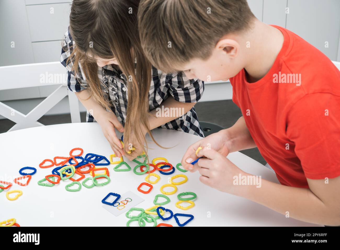 Little school kids play toy constructor standing above kitchen table ...