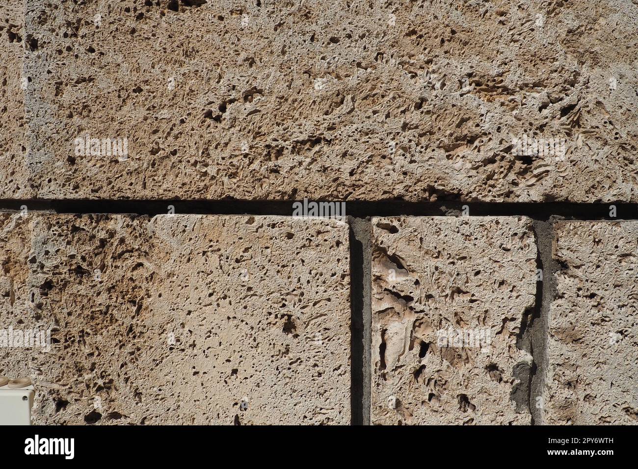 Textured wall lined with beige shell rock tiles. Close-up of a wall ...